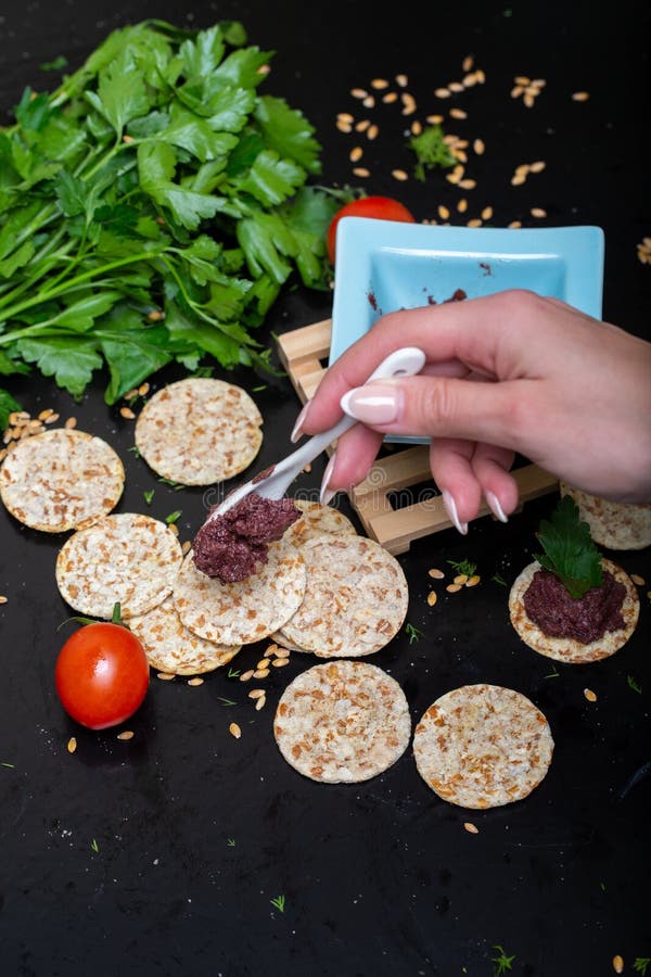 Vertical Closeup of a Person Putting Olive Paste on Crackers on the ...