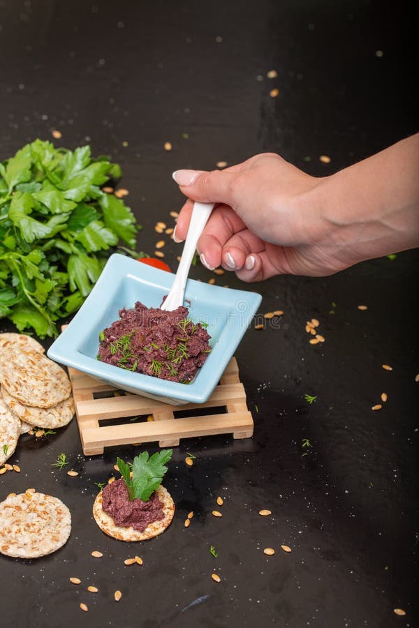 Vertical Closeup of a Person Putting Olive Paste on Crackers on the ...