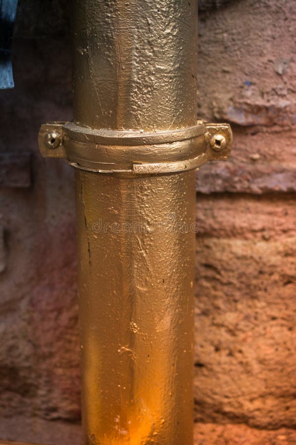 Vertical Closeup of a Pipe Painted Gold, on a Grunge Stone Wall Stock ...