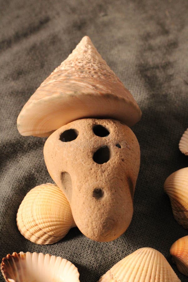 Vertical Closeup of a Small Clay Figure with Multiple Shells on a a ...