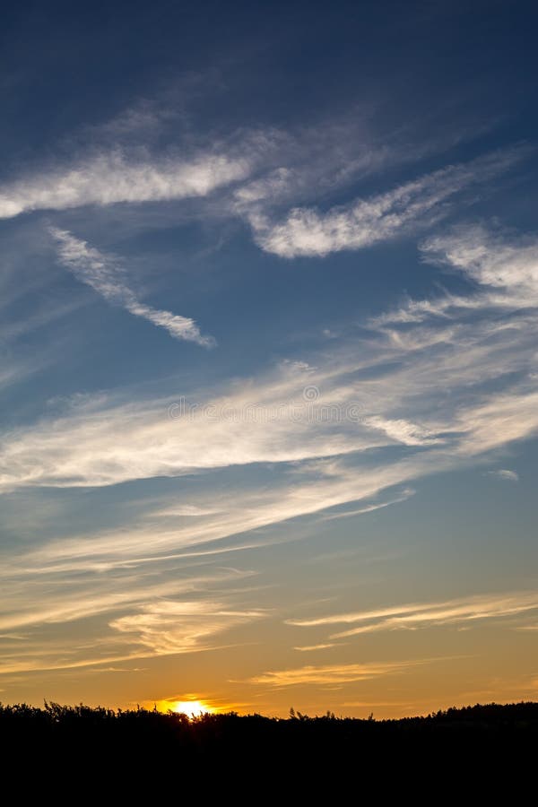 Vertical Cloudscape of Layered Clouds at Sunset with Sun Stock Photo ...