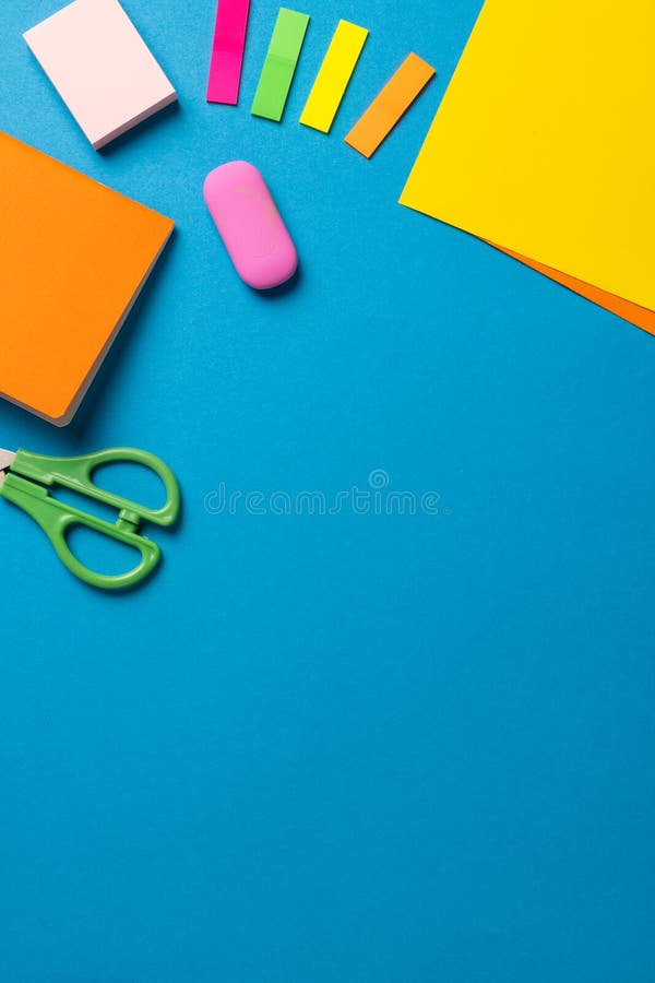 Vertical Composition of Post Its, Eraser, Crayons and Scissors on Blue ...
