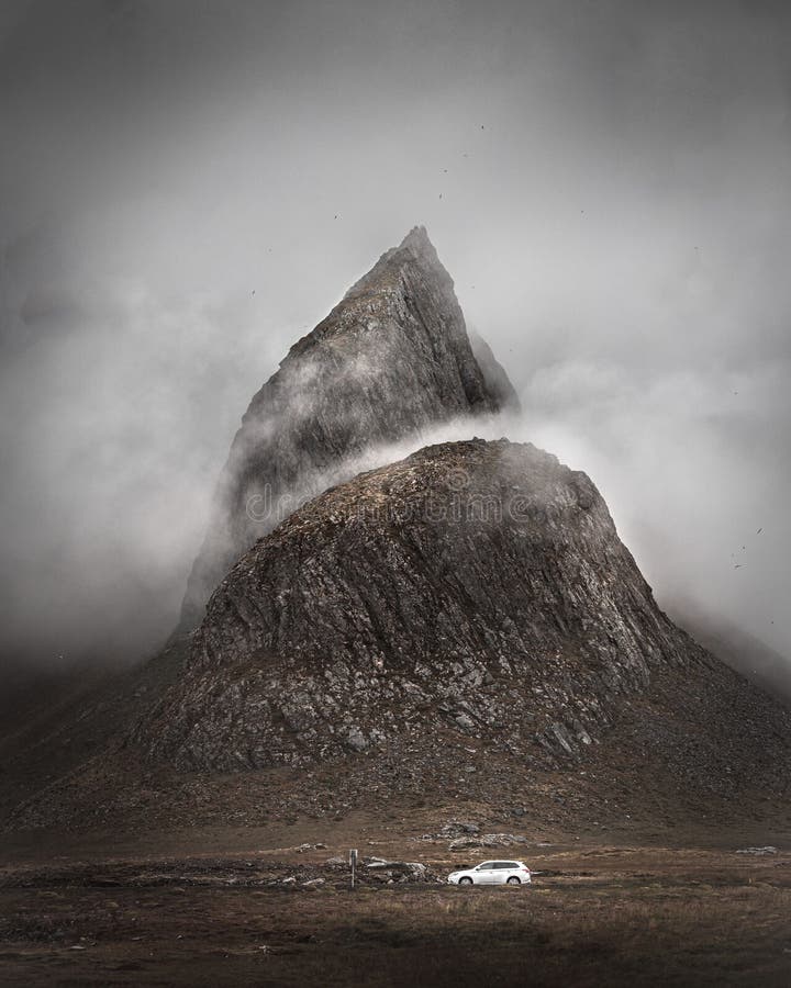 Vertical Distant View of a Car Parked Under a Giant Cliff Covered in ...