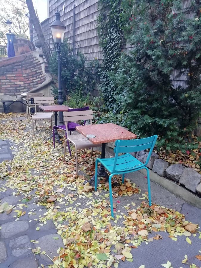 Vertical of Empty Wooden Chairs and Tables Near a Lantern and Wall ...