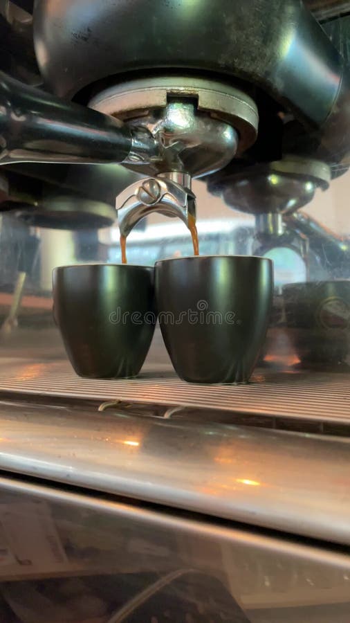 Vertical Flipped Footage of a Coffee Machine Spilling Coffee into Two ...