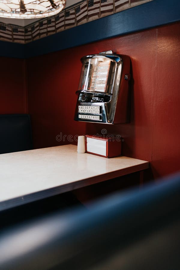 Vertical Focused Shot of a Vintage Jukebox Hanging Near a Table in a ...