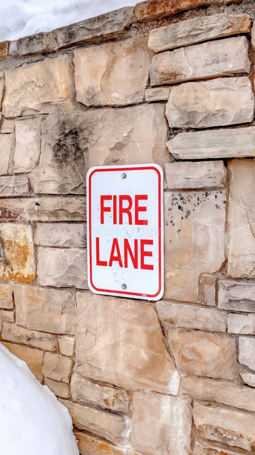 Vertical Frame Fire Lane Sign on Stone Retaining Wall Amid Thick Fresh ...