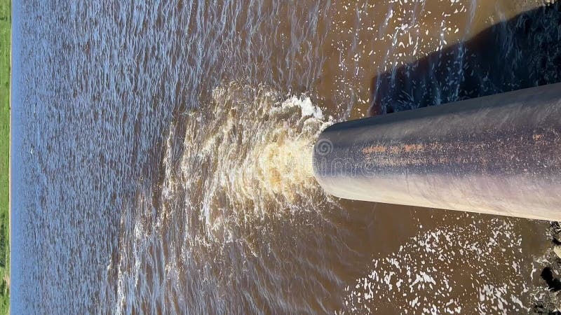 Vertical Frame. Water Flows Out of a Large Steel Pipe into a Wide River ...