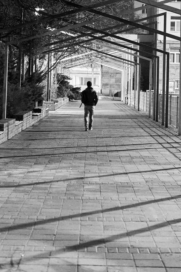 Vertical Greyscale Shot of a Male Walking through a Sidewalk Stock ...