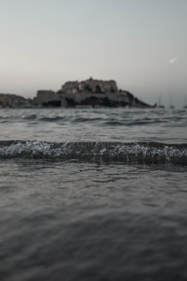 Vertical Greyscale Shot of the Waves of Water with Mountains in the ...