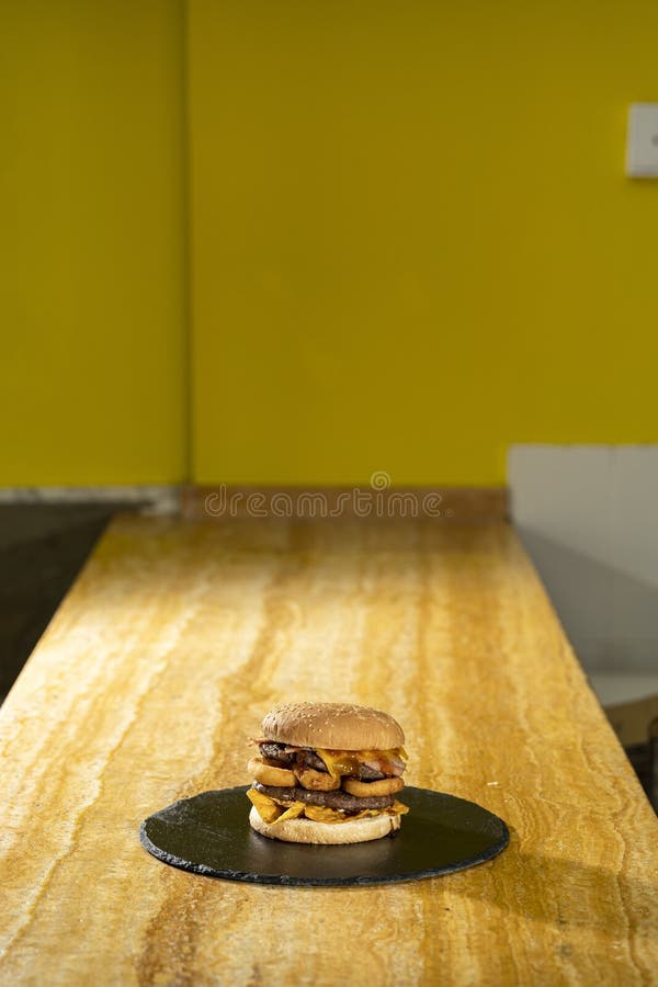 Vertical High Angle Shot of a Burger on a Black Round Board on a Wooden ...