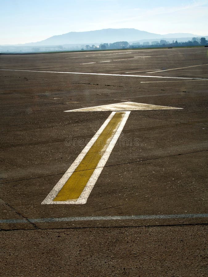 Vertical high angle shot of a yellow-painted arrow on the ground ...