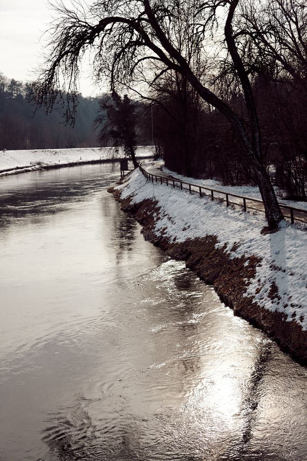 Vertical High-angle of a Sunlit River with Trees Around Snow on the ...