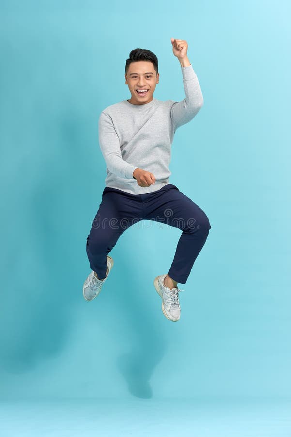Vertical Image of Asian Man Jumping in Studio. Isolated Blue Background ...