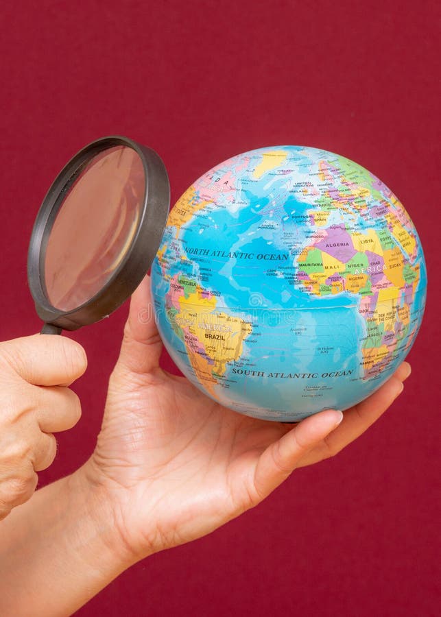Vertical Image of a Hand Holding a Magnifying Glass Over an World Globe ...