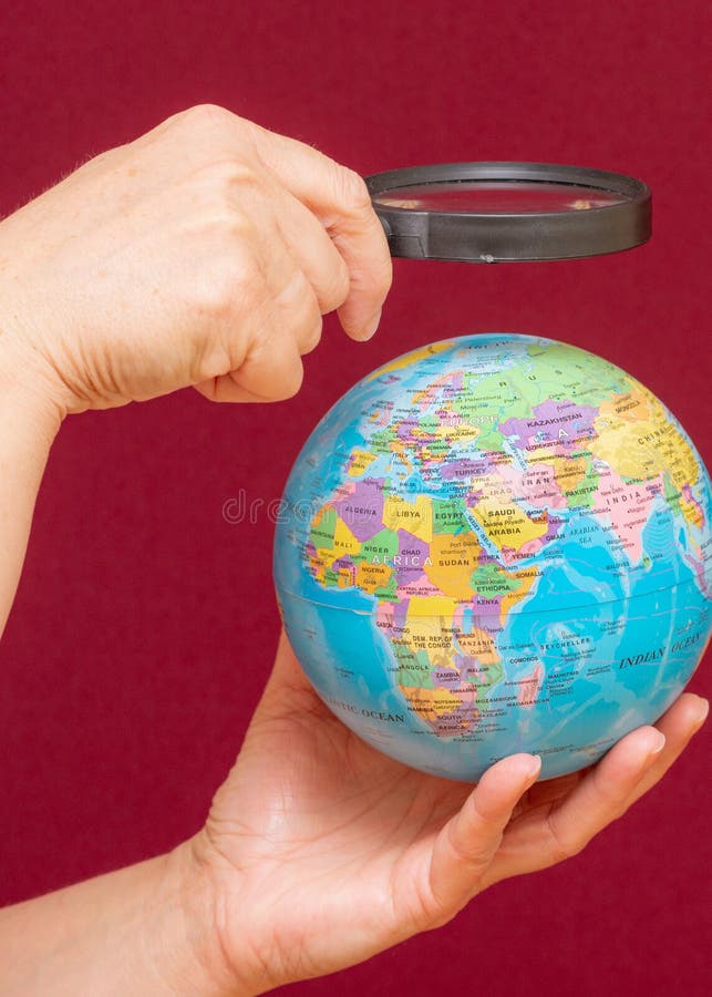 Vertical Image of a Hand Holding a Magnifying Glass Over an World Globe ...