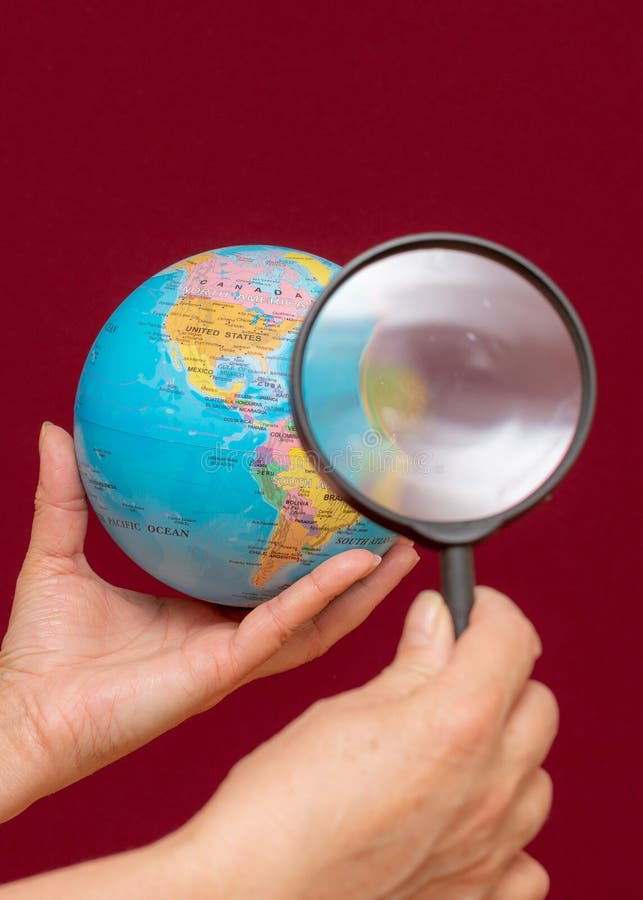 Vertical Image of a Hand Holding a Magnifying Glass Over an World Globe ...