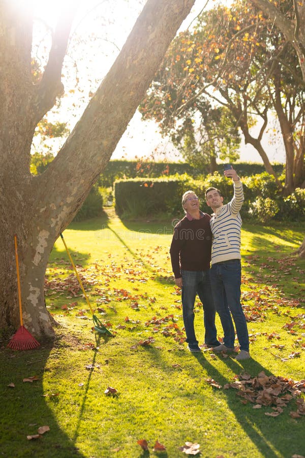 Vertical Image Of Happy Caucasian Father And Adult Son Taking Selfie In