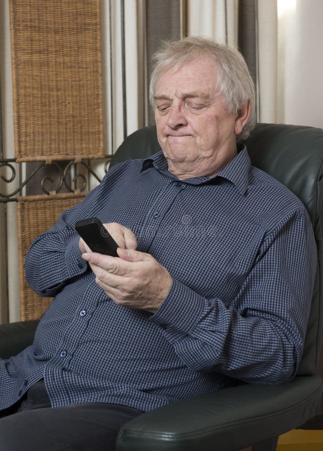 Vertical Image of a Mature Man Looking Down at a Phone Looking Annoyed ...