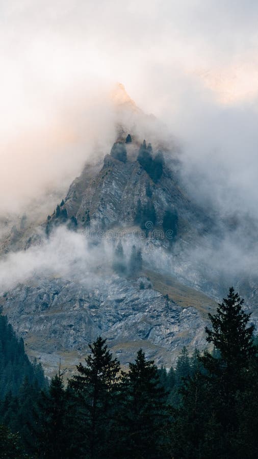 Vertical Image of a Mountain Covered by a Layer of Wispy Clouds ...