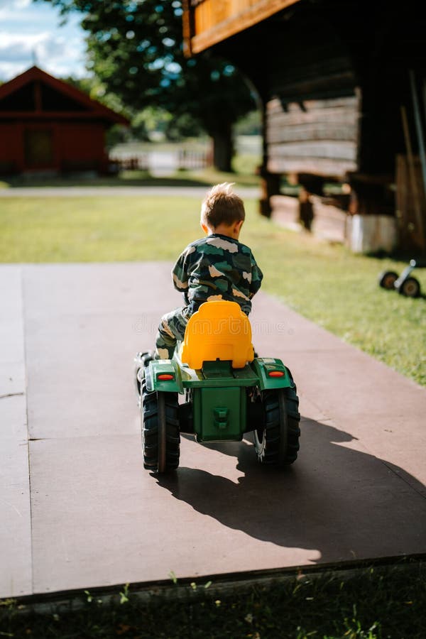 Vertical of a Kid Driving a Toy Car in the Yard. Stock Image - Image of ...
