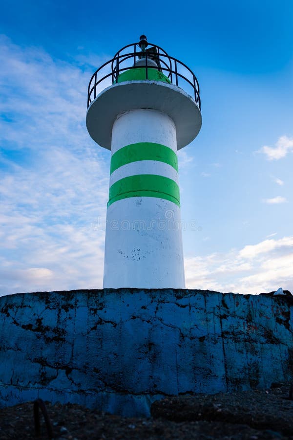 Vertical Low Angle Shot of a Green White Lighthouse in a Bright Blue ...