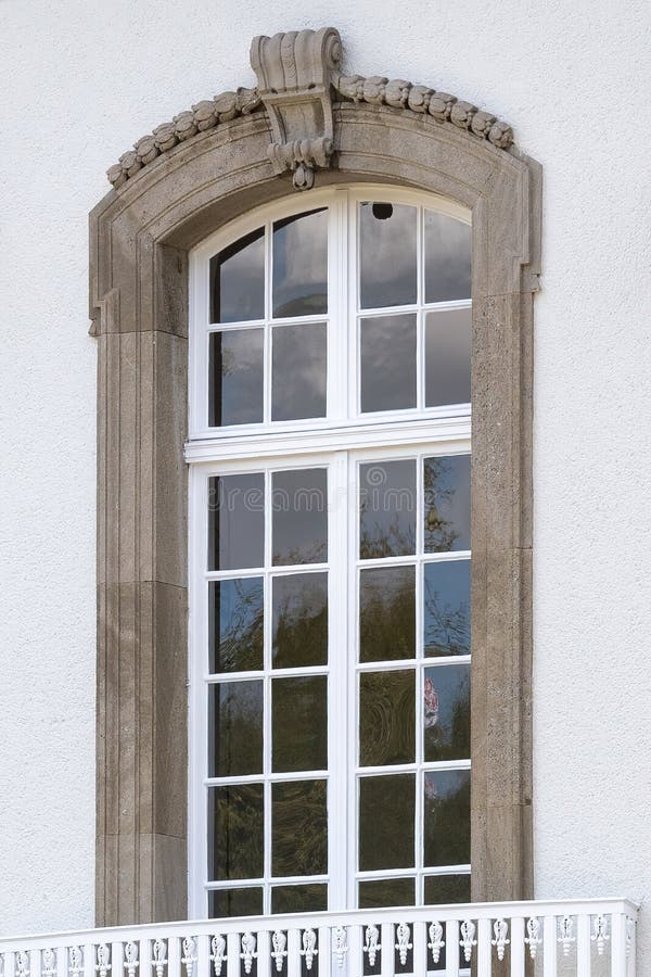 Vertical of an Old Fashioned Window with a White Balcony Fence in Front ...