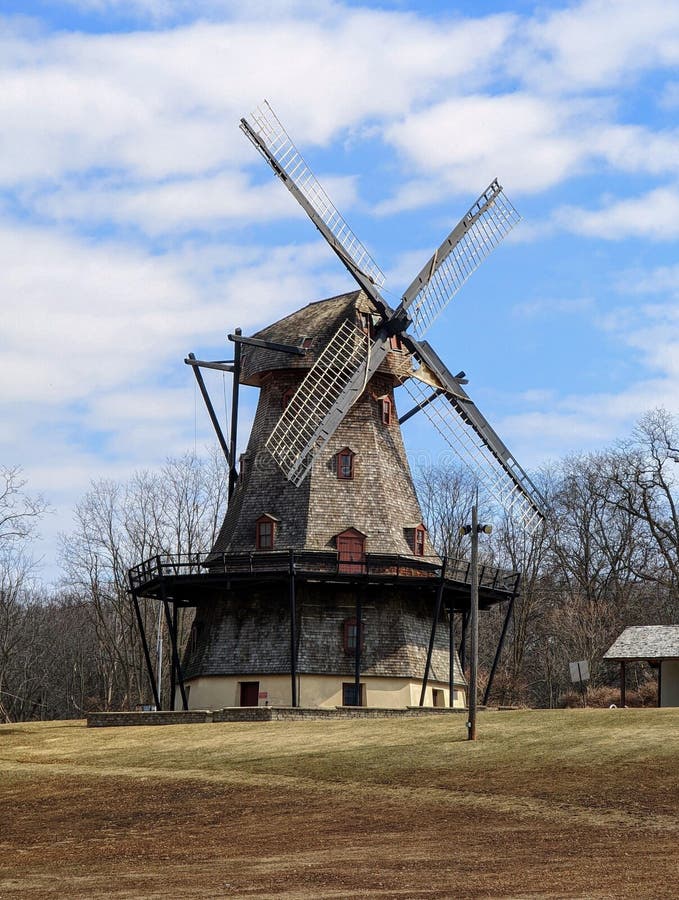 Vertical of an Old Windmill in a Field Under a Cloudy Blue Sky Stock ...