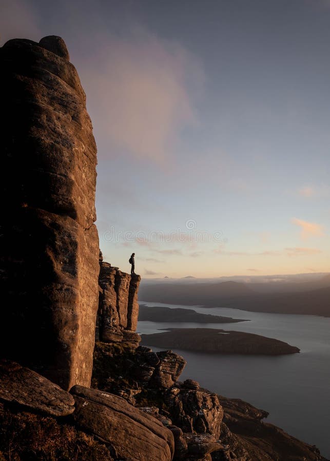 Vertical of a Person Standing on a Rocky Shoreline Enjoying the Sunset ...