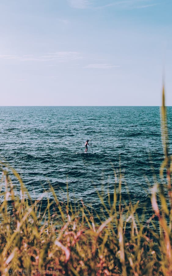 Vertical of a Person Surfing in the Distance in Ocean. Stock Photo ...