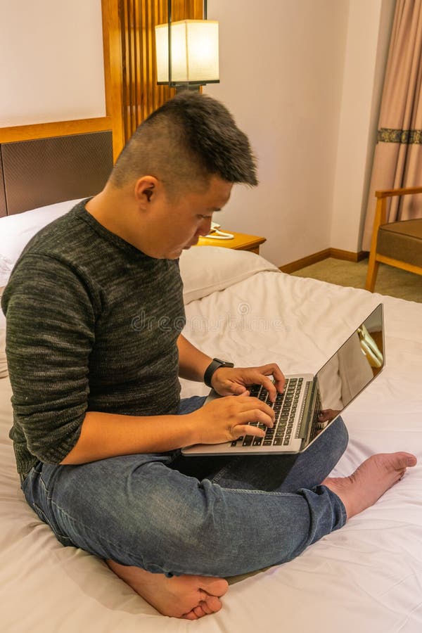 Vertical Photo of Asian Man Using Laptop on Bed Stock Photo - Image of ...