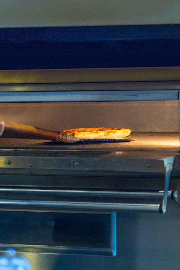 Vertical Photo of Baker Using Tool Picking Pizza in Oven Stock Photo ...