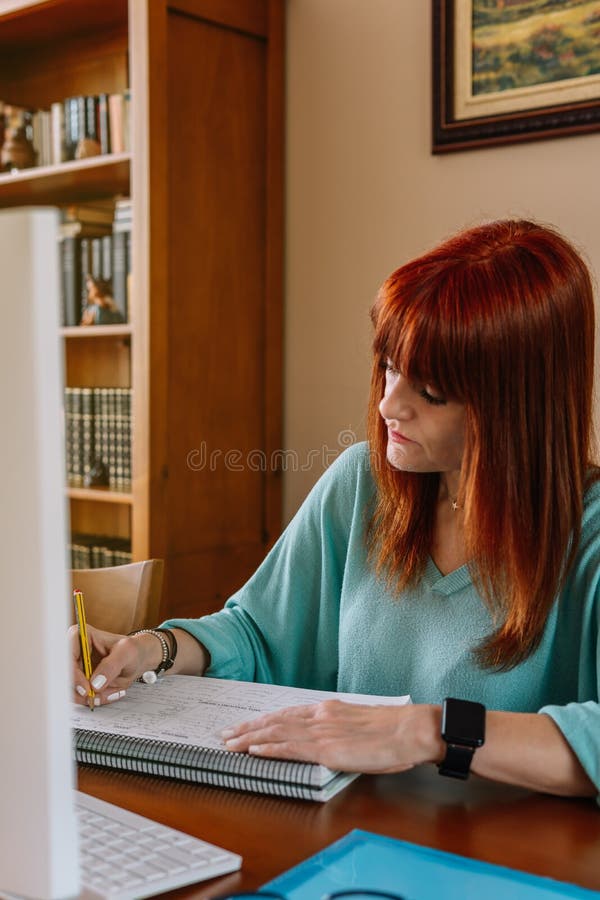 Vertical Photo of a Woman Writing in a Notebook while Teleworking Stock ...