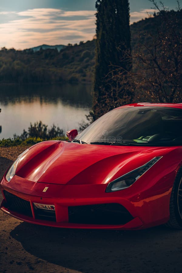 Vertical of a Red Ferrari Parked Against a Beautiful Sight of a Lake at ...