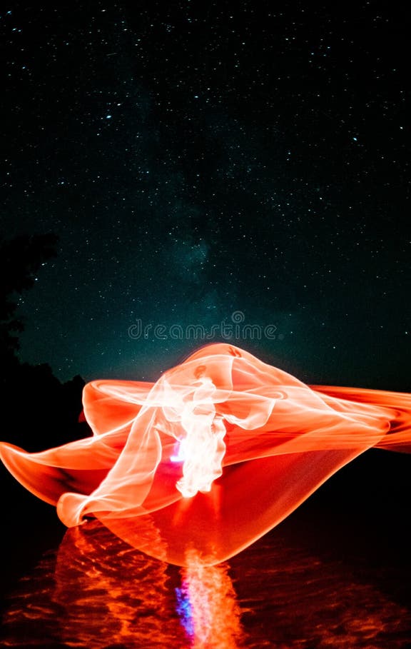 Vertical of a Red Magical Pattern Reflecting on Water Against a Starry ...