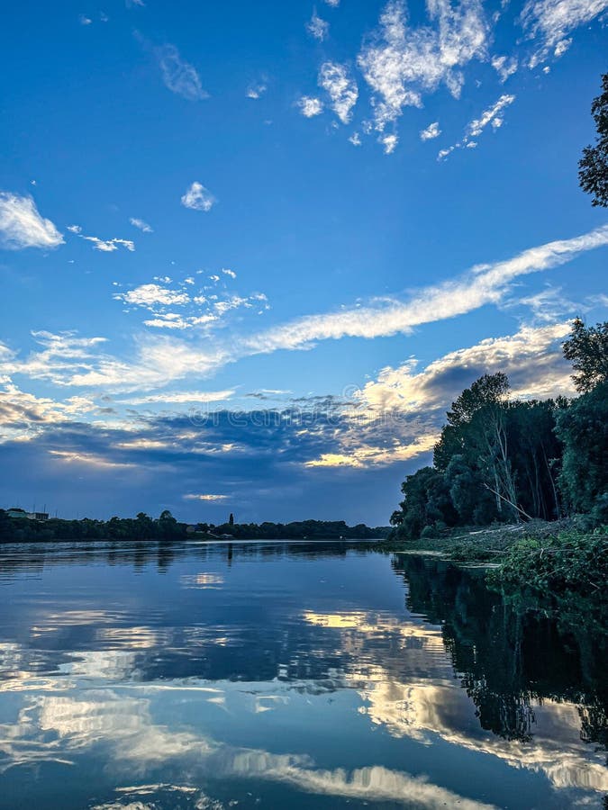 Vertical of a River Reflecting Blue Sky and Clouds, Trees on the Bank ...