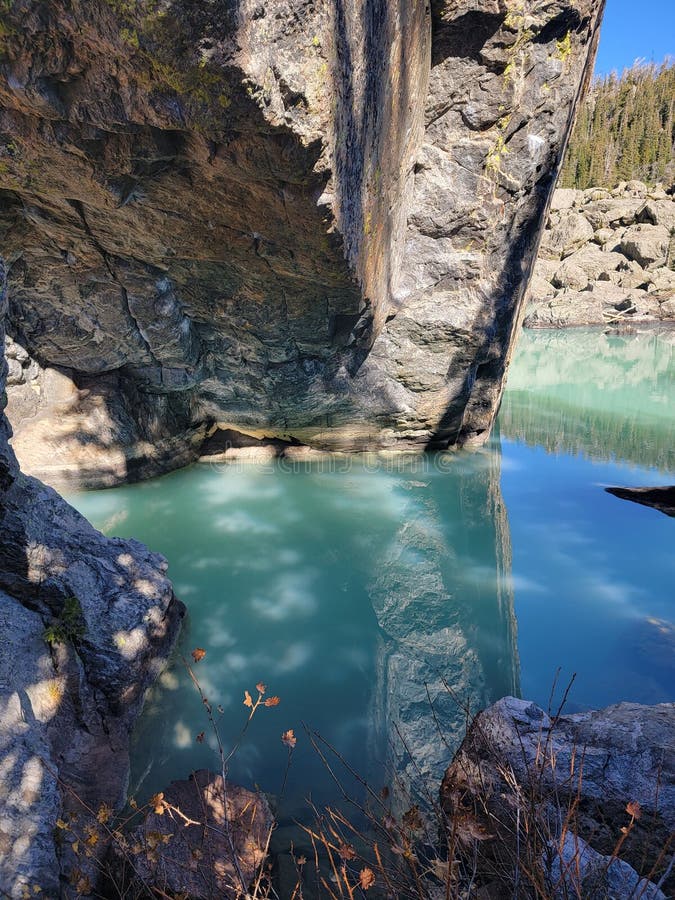 Vertical of a Rock Reflecting in the Water. Stock Image - Image of ...
