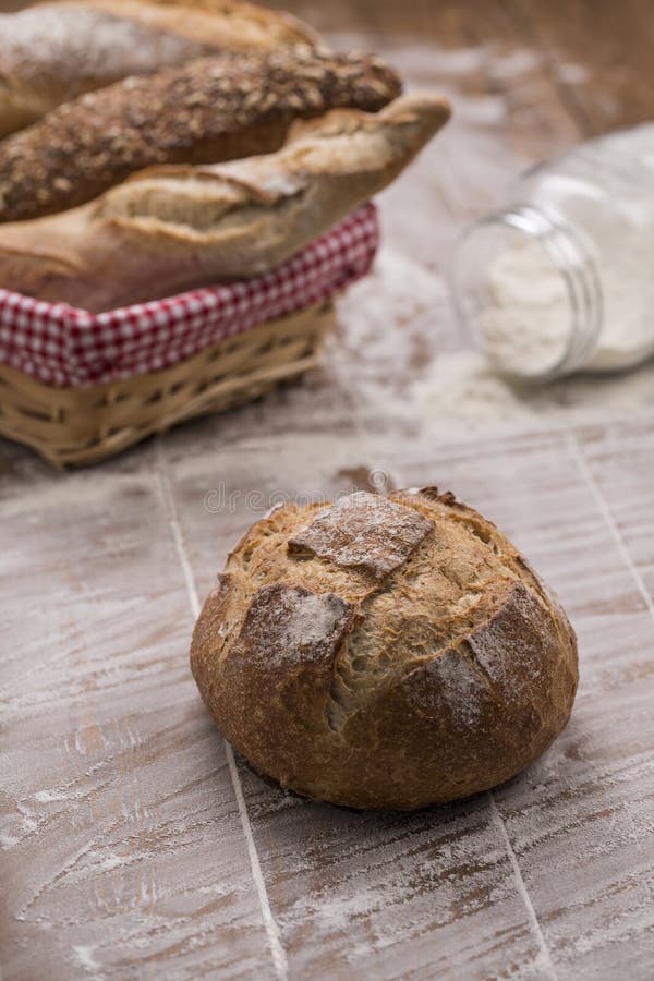 Round Bread with Basket of Various Bread Forms on Wooden Table Stock ...