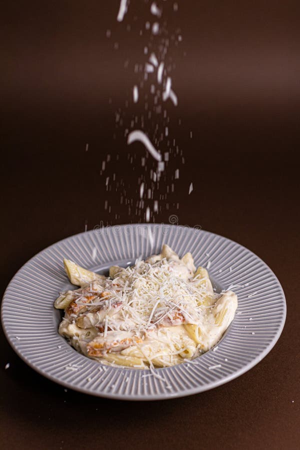 Vertical Shot of Adding Cheese To a Plate of Hot Macaroni with Chicken ...