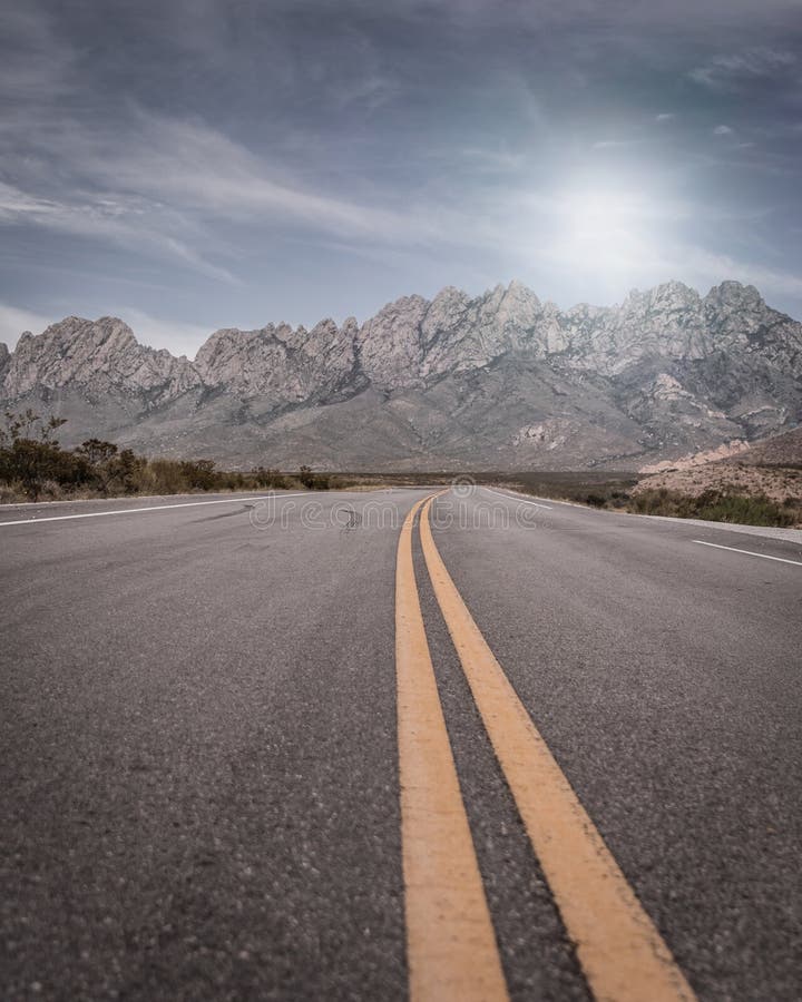 Vertical Shot of a Asphalt Road with Two Yellow Strips and a Mountains ...