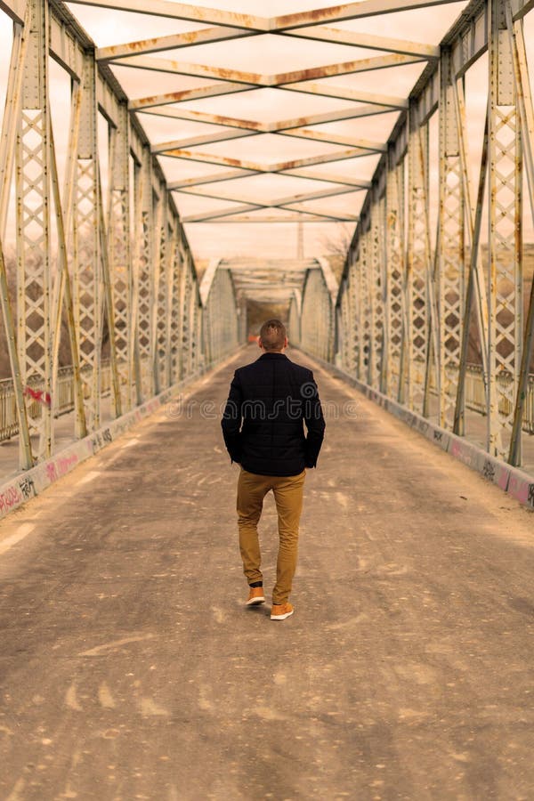 Vertical Shot of a Back of a Man Walking on a Bridge. Stock Photo ...