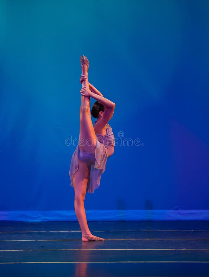 Vertical Shot of a Ballerina Standing in a High Kick Pose on a Stage ...
