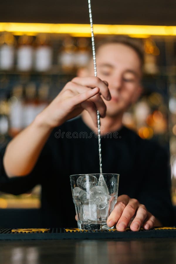 Vertical Shot of Bartender Stirring Ice Cubes in Glass Using Long Bar ...