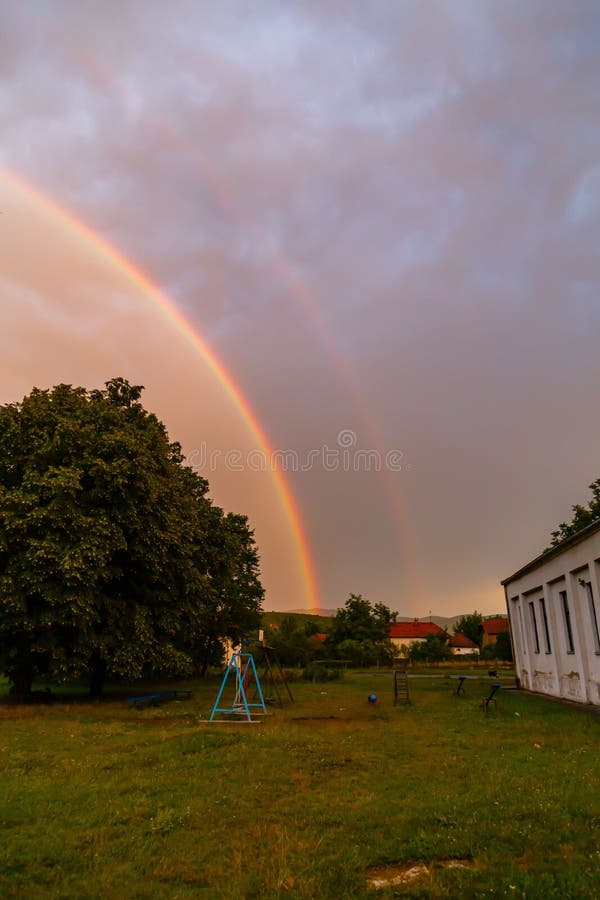 Vertical Shot of the Beautiful Rainbow Shining in the Gloomy Sky Over ...