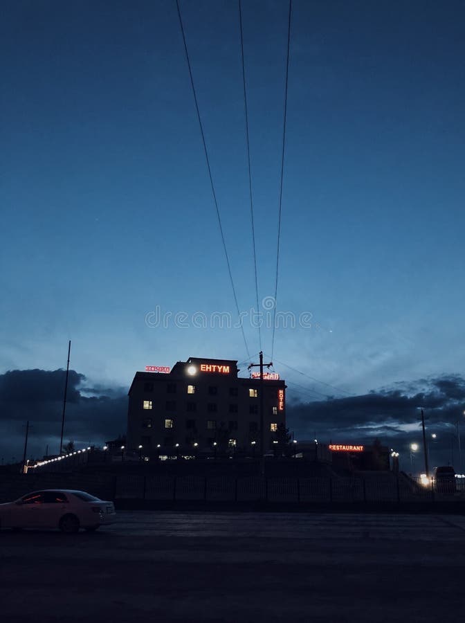Vertical Shot of a Big Building with Red Neon Signs Under a Cloudy Sky ...