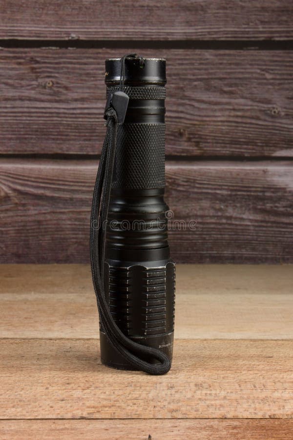 Vertical Shot of a Black Technical Torch Light on a Wooden Surface ...