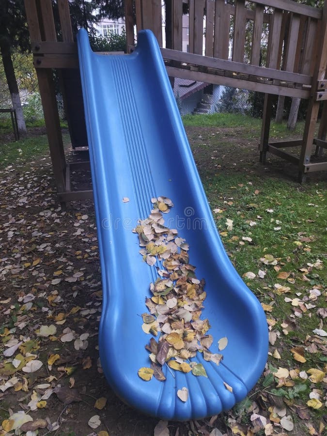 Vertical Shot of a Blue Slide Playground with Autumn Leaves on it Stock ...