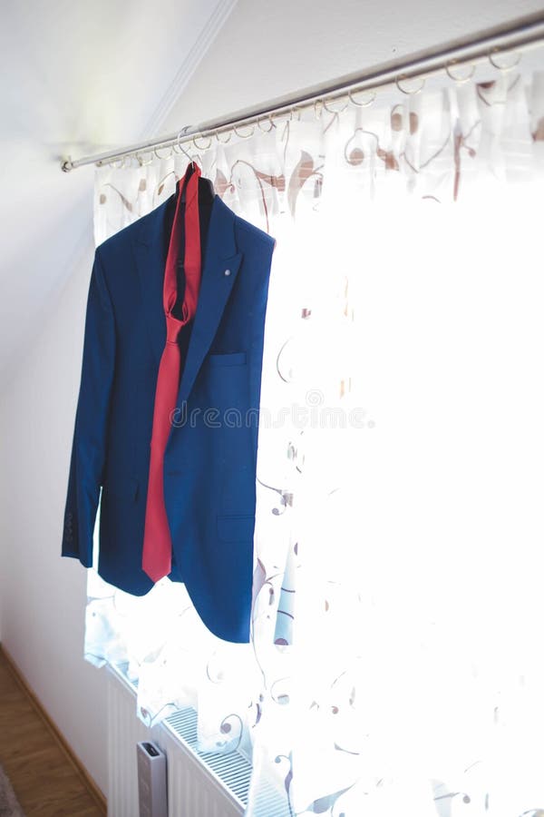 Vertical Shot of a Blue Stylish Jacket with a Red Tie Hanging on a Rack ...