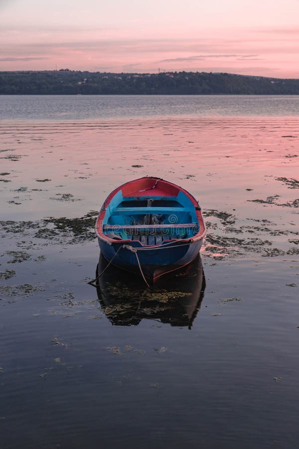 Vertical Shot of a Boat on a Calm Sea Against a Sunset Sky Stock Photo ...