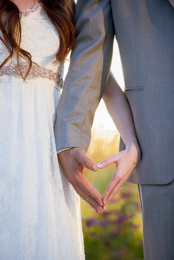 Vertical Shot of the Bride and the Groom Making a Heart Shape with ...